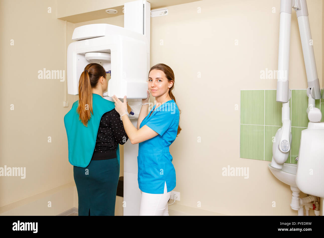 Young woman patient standing in x-ray machine. Panoramic radiography ...