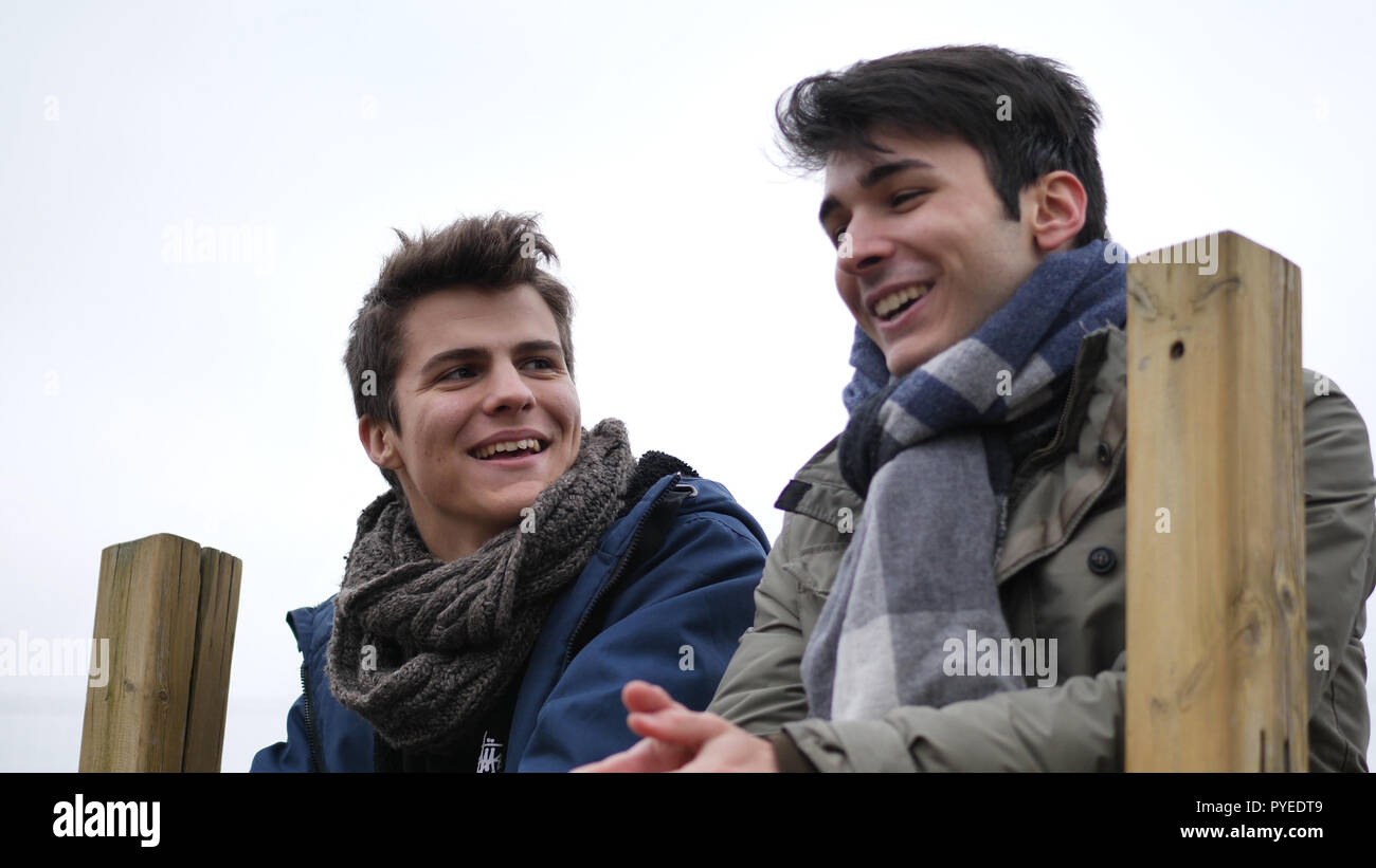 From below view of young men in winter clothing talking while chilling ...