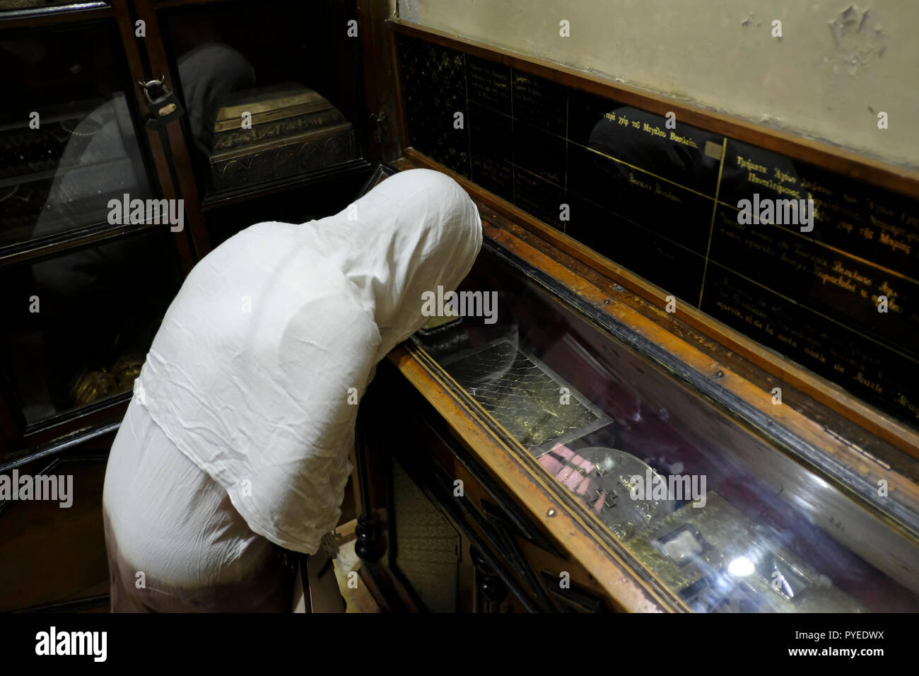 An eastern orthodox pilgrim prays over a wooden reliquary case ...
