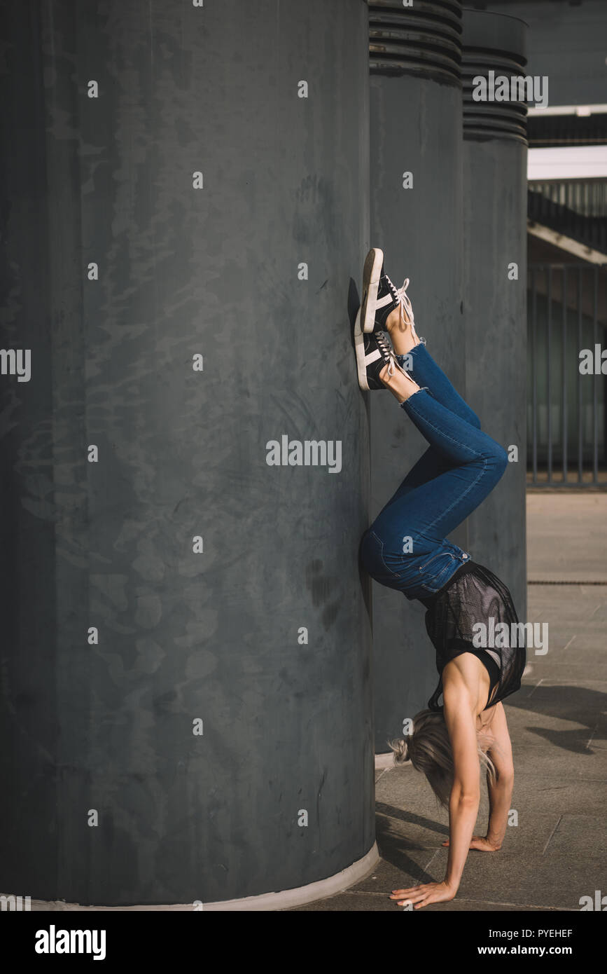 beautiful young woman performing handstand near black column Stock ...