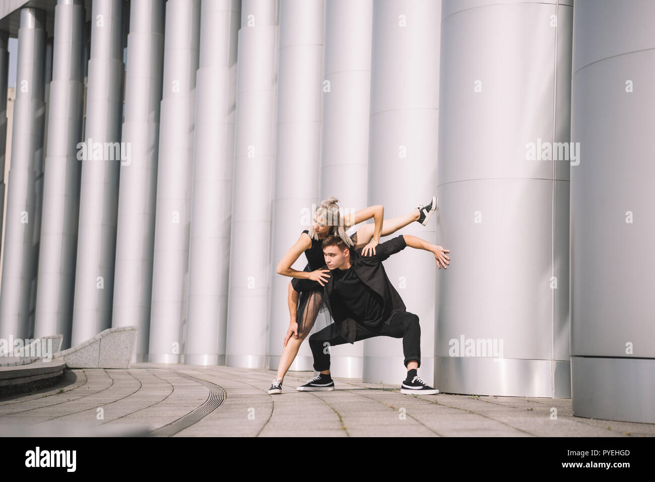 beautiful young performers in black clothes dancing near columns on ...