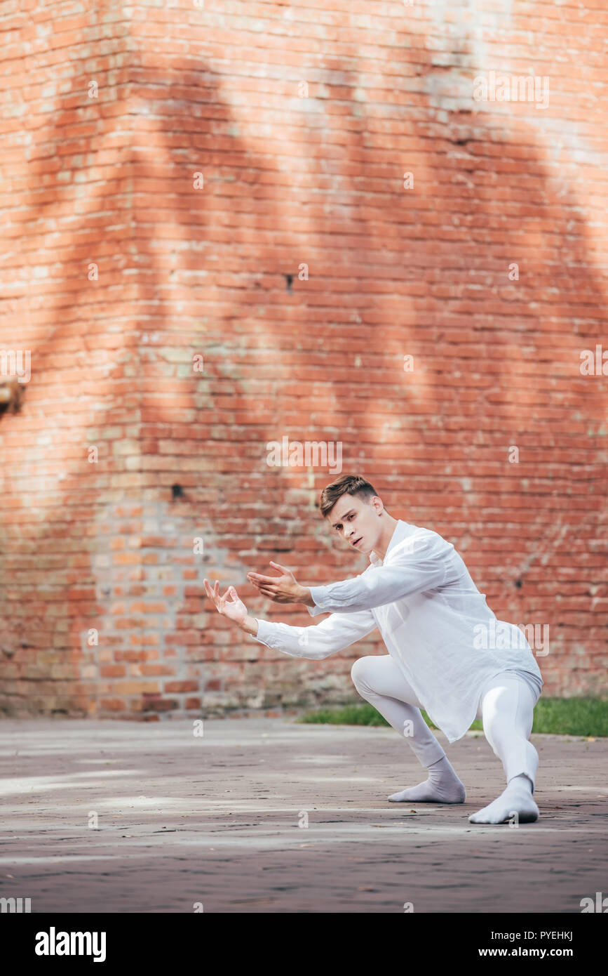 handsome young male ballet dancer in white clothes dancing on urban ...