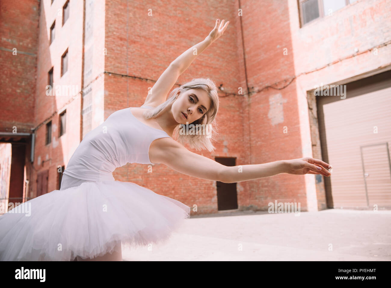 low angle view of young ballerina looking at camera while dancing on ...