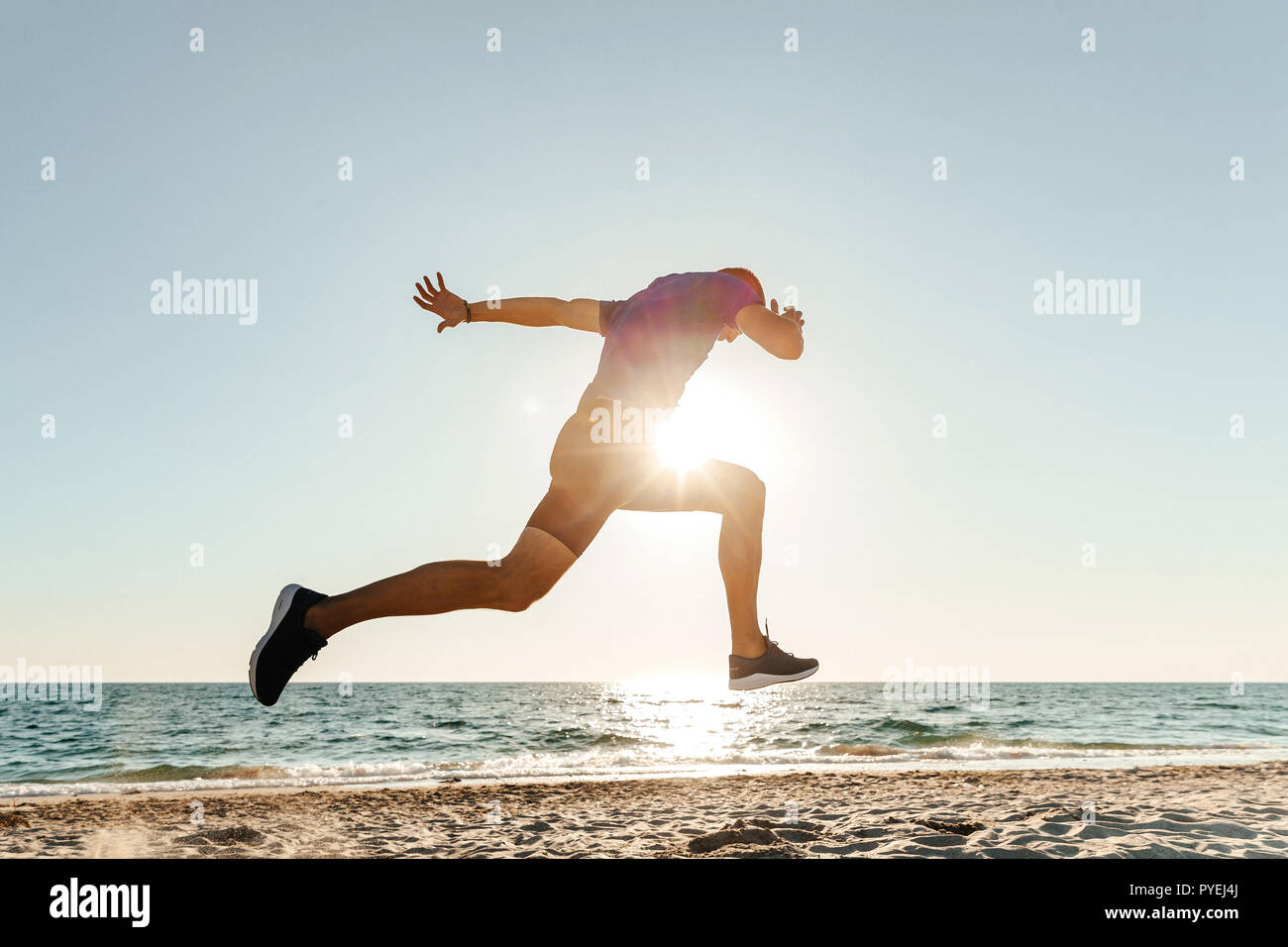 fast athlete runner running along sea coast in sunlight Stock Photo - Alamy