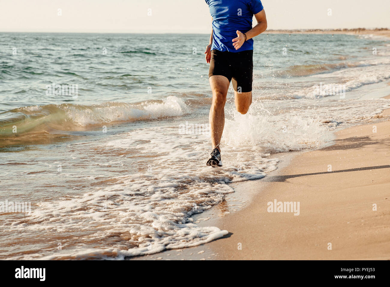 man runner running on waves of sea beach, water spray Stock Photo - Alamy