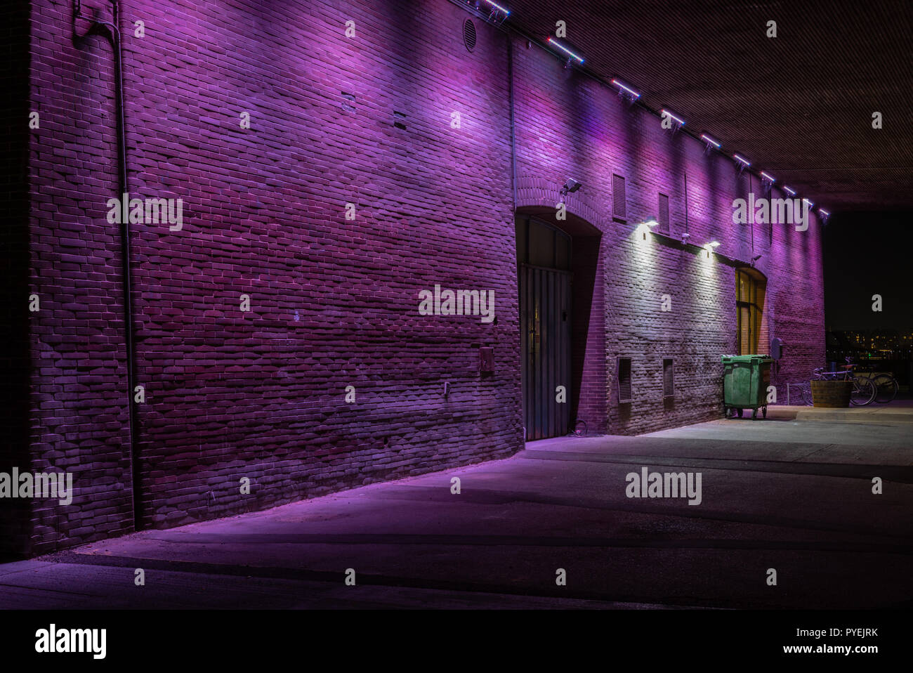 A violet illuminated underpass below an highway bridge in Copenhagen in ...