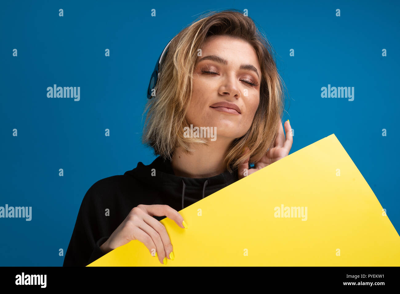 Portrait of girl with headphones and eyes closed, enjoying music while ...