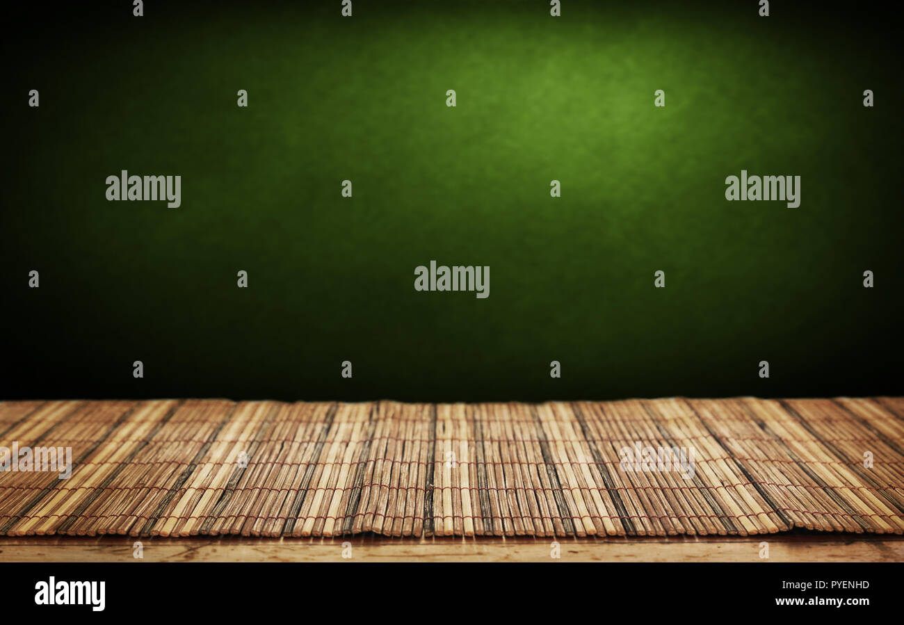 Empty bamboo table and green wall in background Stock Photo - Alamy