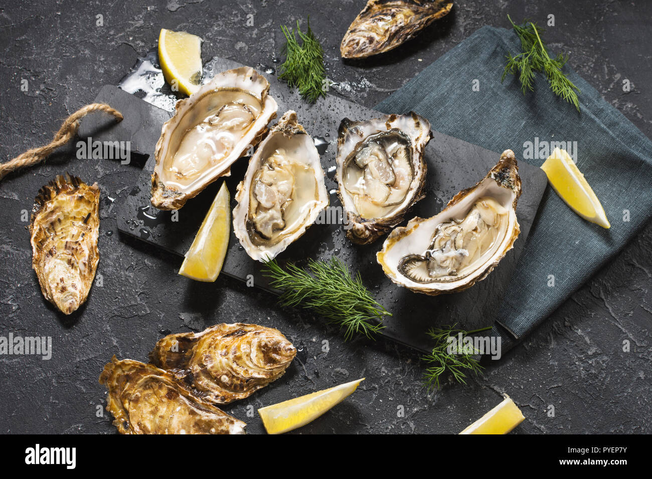 Opened Oysters with lemon on dark stone texture background Stock Photo ...