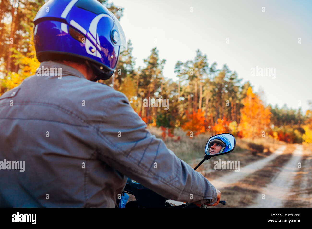 Senior man riding scooter on autumn forest road. Driver in helmet ...