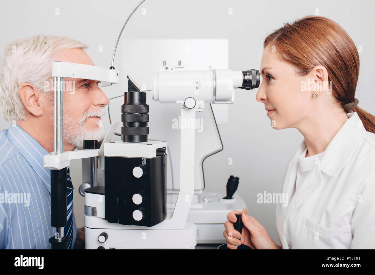 doctor Optometrist examining old man's eyes with special eye equipment ...