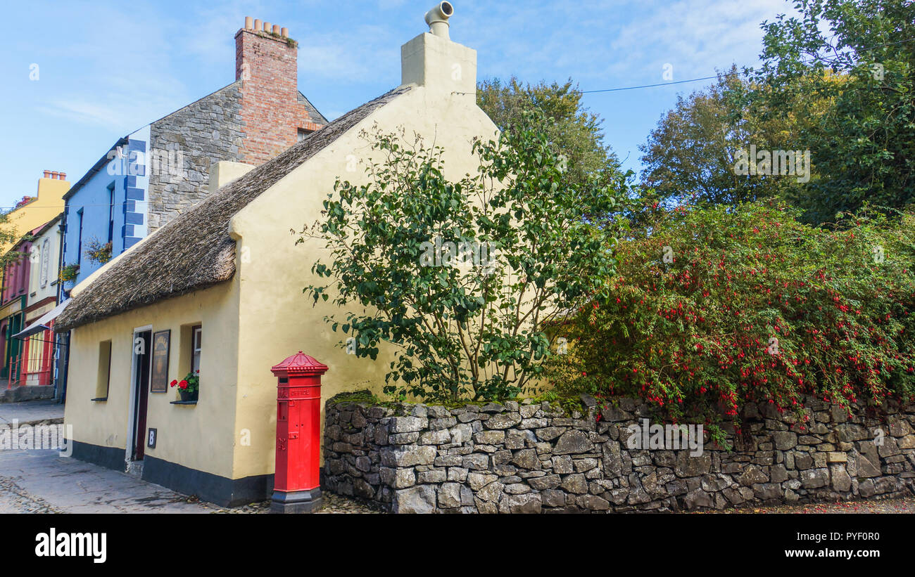historic village street with red mailbox, flowering red fuchsias ...