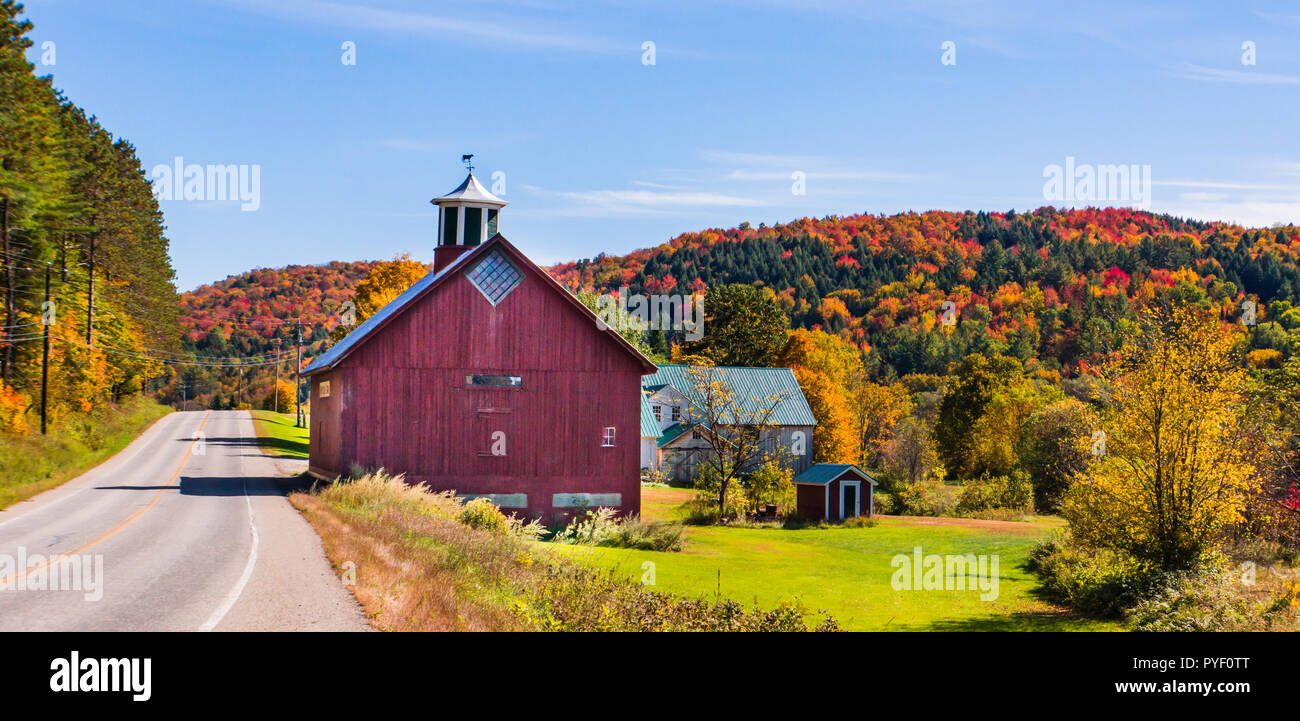 country road with red barn along a country rural road with woods ...