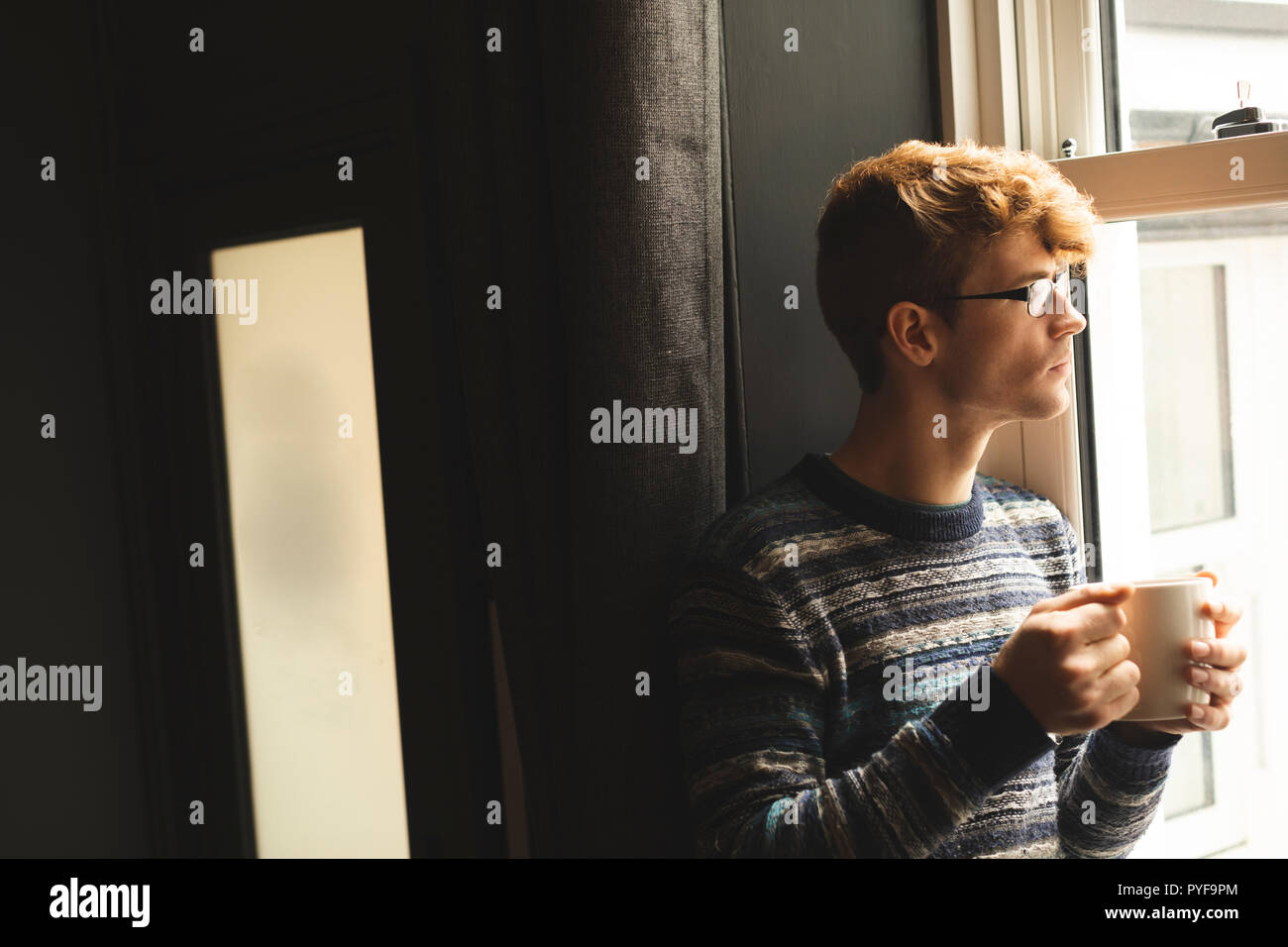 Man having coffee while looking through window Stock Photo - Alamy