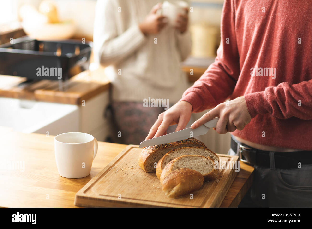 Man cutting a loaf of bread in kitchen Stock Photo - Alamy