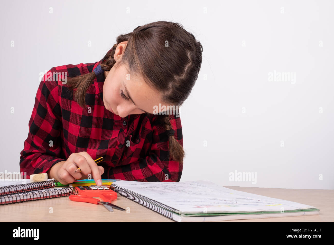 Concentrated girl using calculator on study table Stock Photo - Alamy