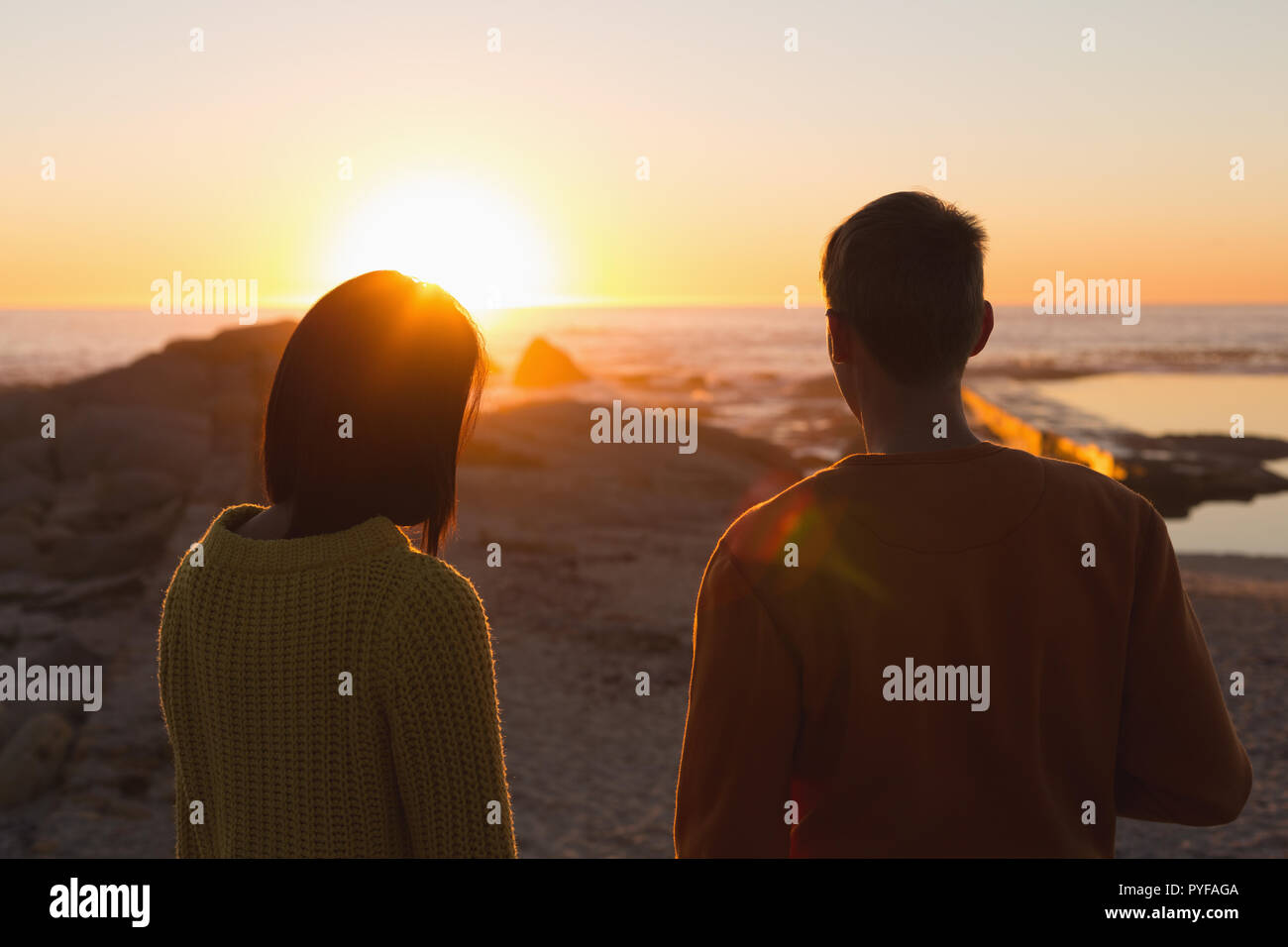Couple standing on beach during sunset Stock Photo - Alamy