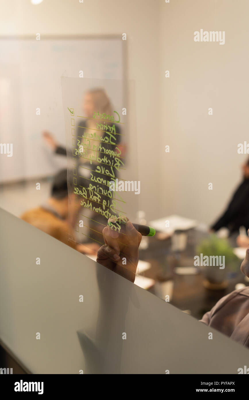 Female executive writing on glass wall in office Stock Photo - Alamy