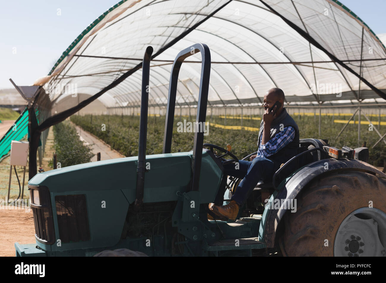 Man talking on mobile phone while sitting on tractor Stock Photo - Alamy