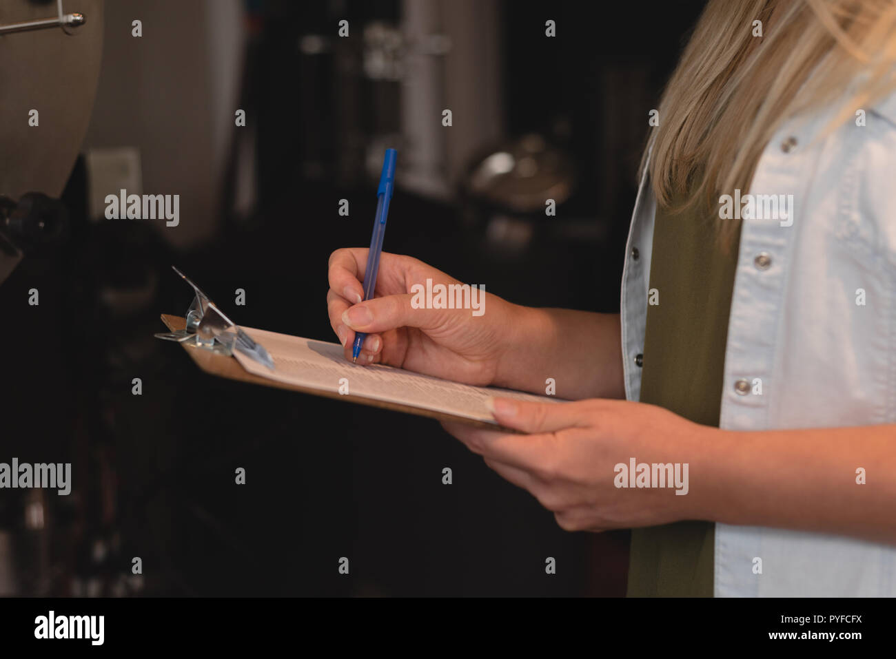Female worker writing on clipboard in factory Stock Photo - Alamy