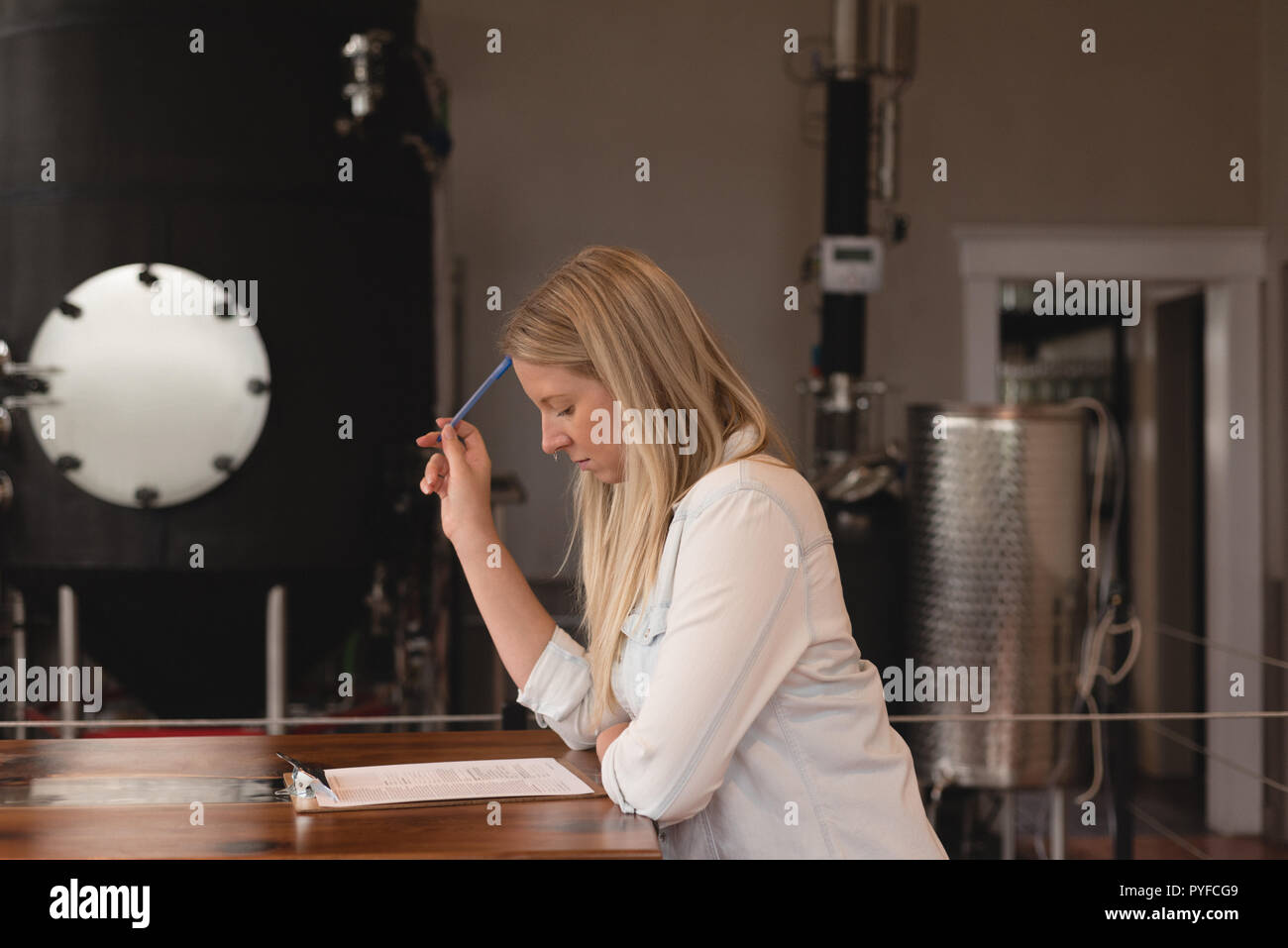 Female worker writing on clipboard in factory Stock Photo - Alamy