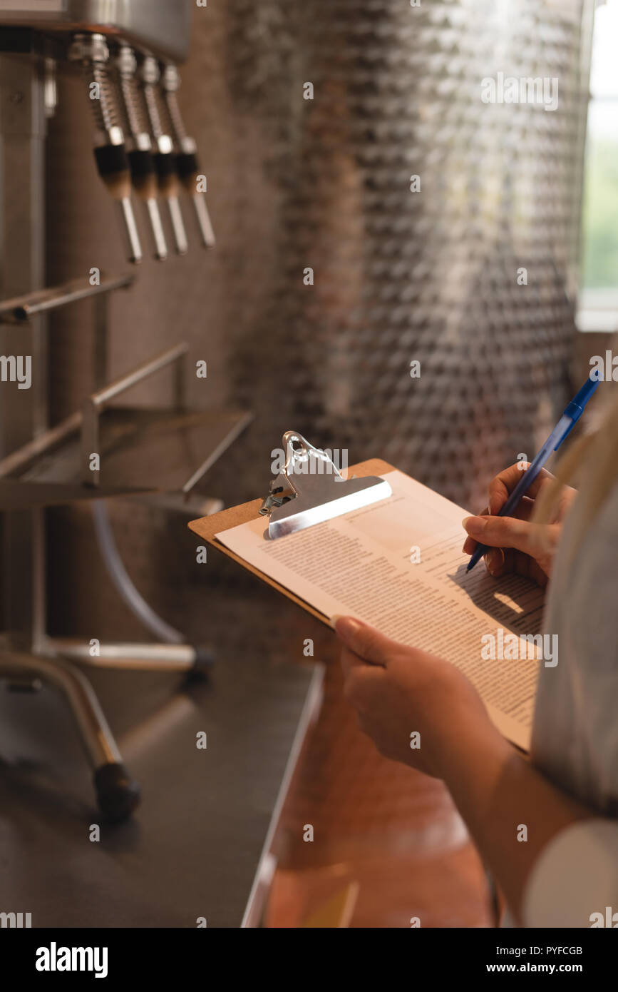 Female worker writing on clipboard in factory Stock Photo - Alamy
