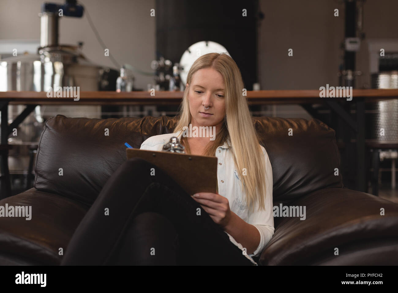 Female worker writing on clipboard in factory Stock Photo - Alamy