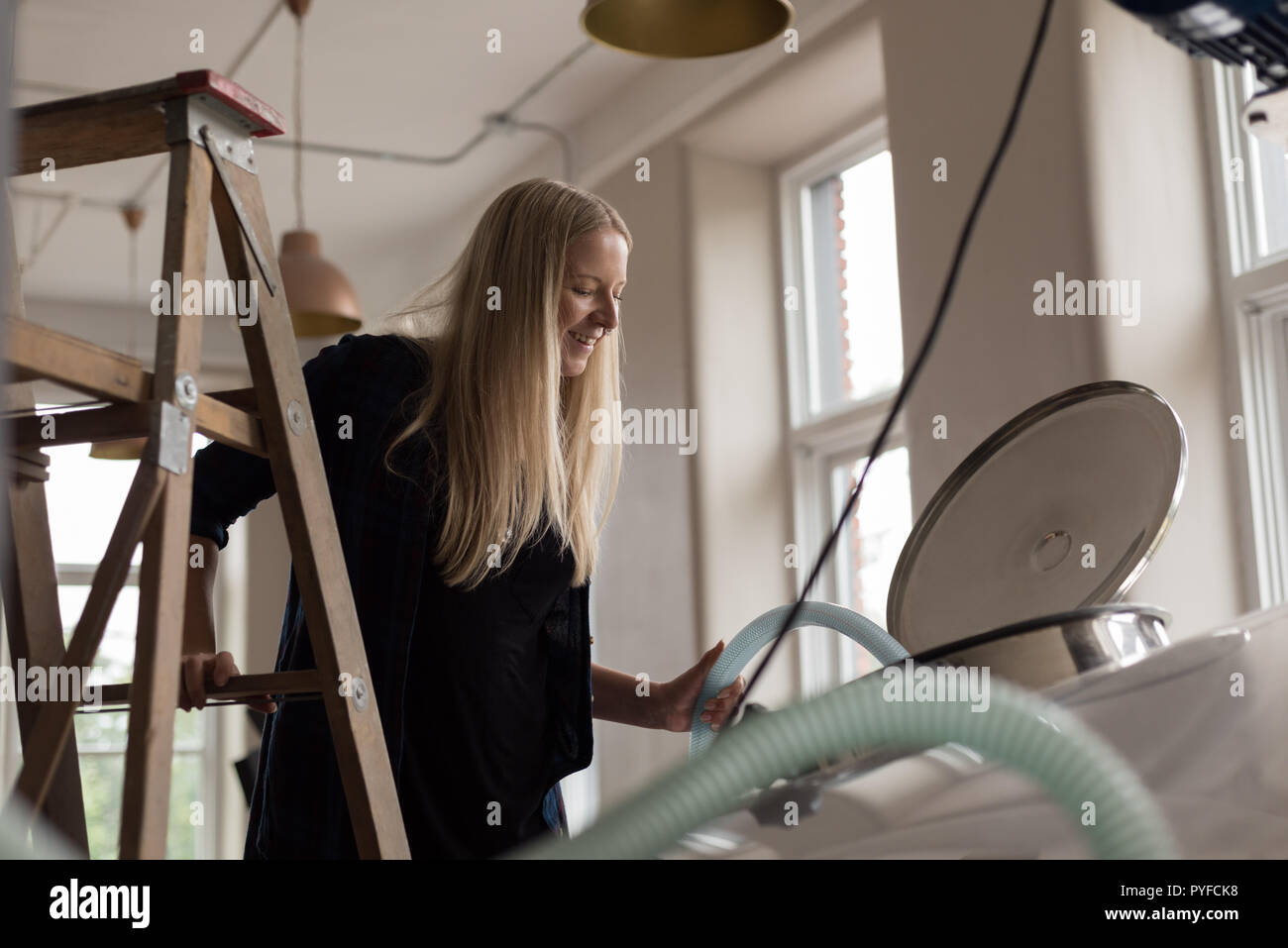 Female worker filling water in distillery tank at factory Stock Photo ...