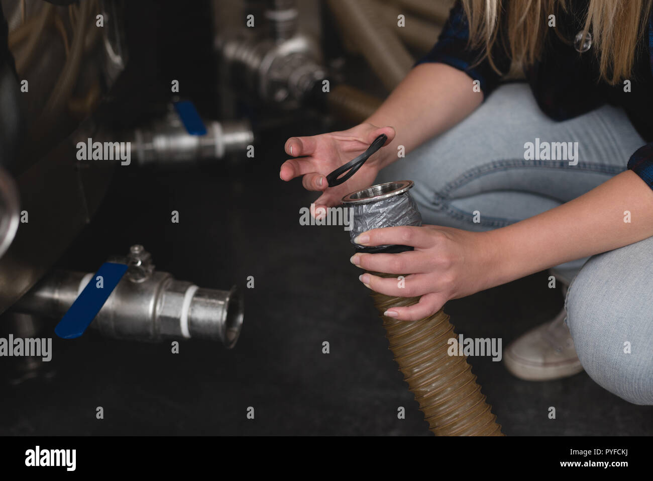 Female worker checking pipe of distillery tank Stock Photo - Alamy