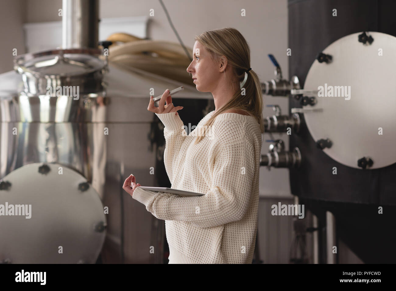 Female worker talking on mobile phone in factory Stock Photo - Alamy