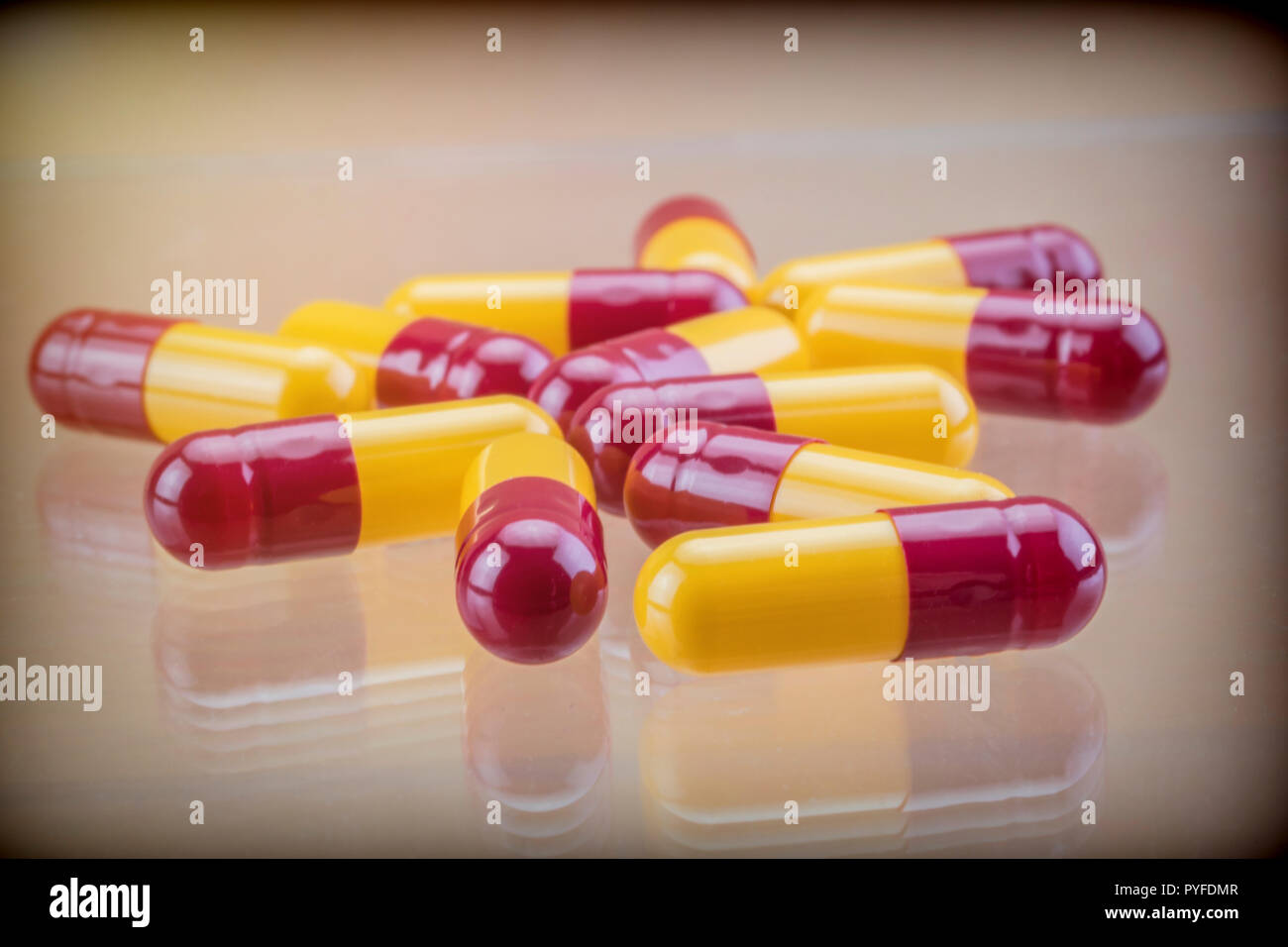 Some aligned red and yellow capsules isolated on brown fund, conceptual ...