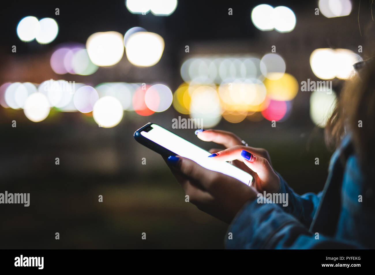 Using cellphone at night - with defocused city lights in the background ...