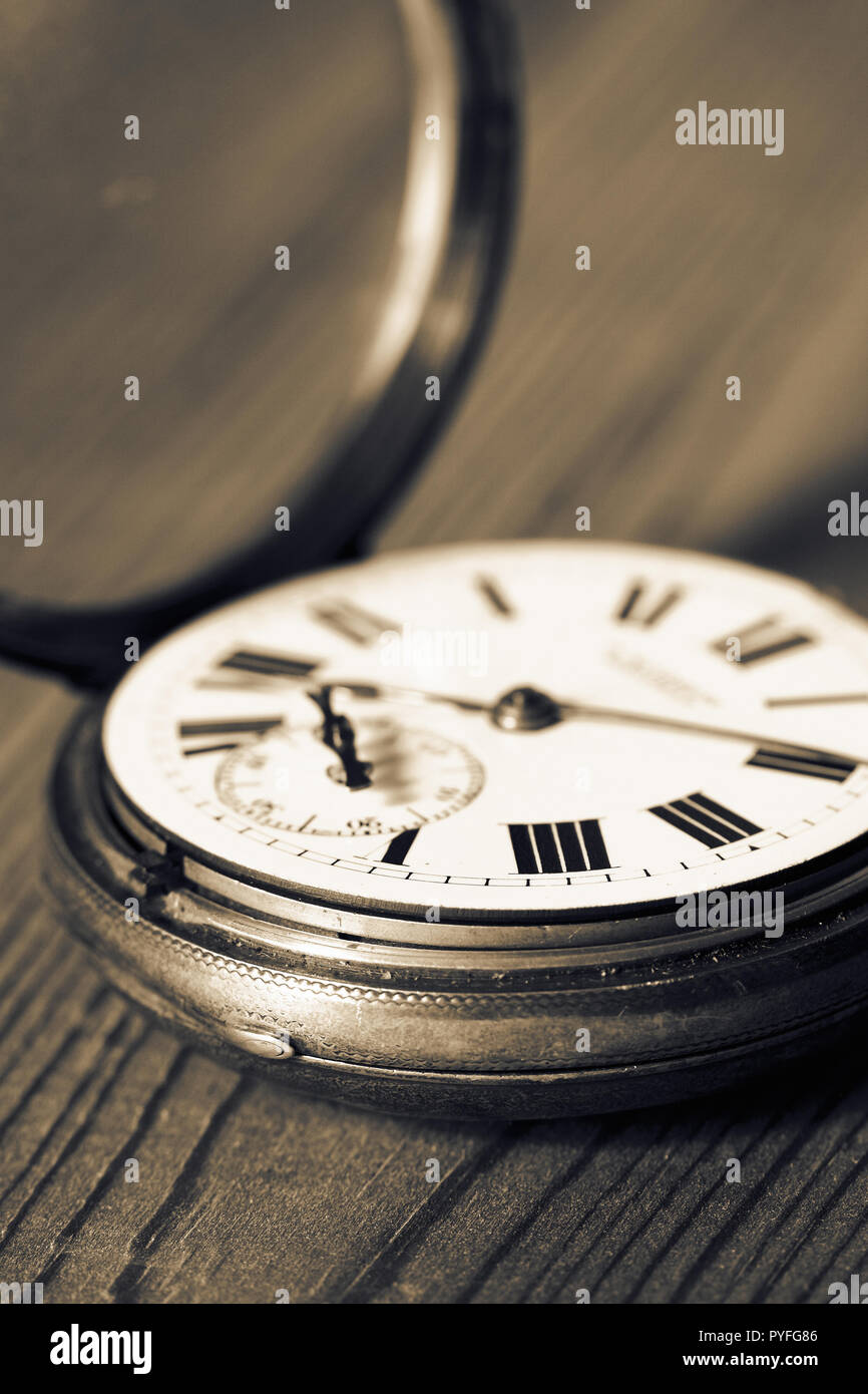 Antique old pocket fob watch on a wood background with sepia toning ...