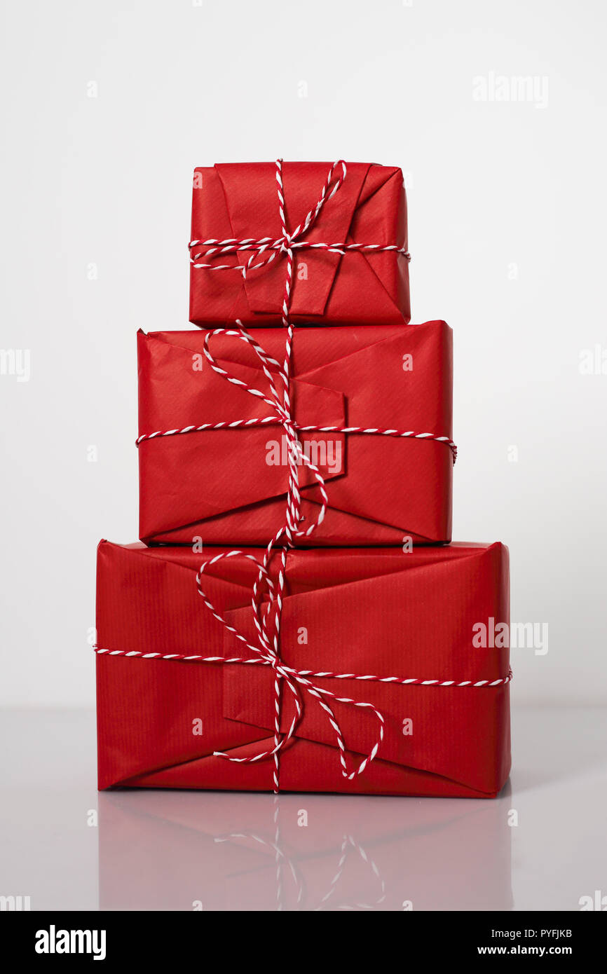 Christmas gift boxes wrapped in red paper and bow of dtriped rope on ...