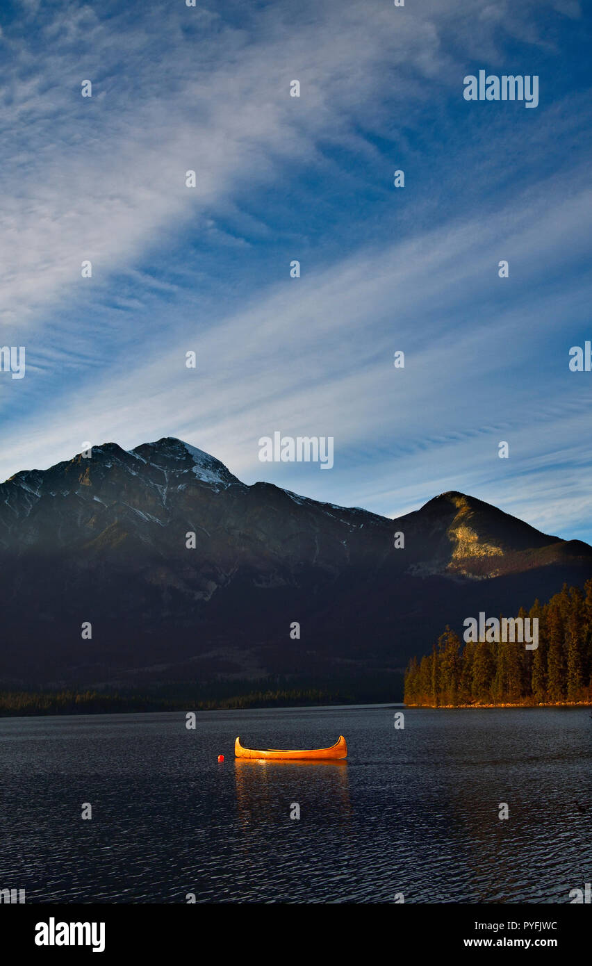 A vertical image of a cedar strip canoe floating on a calm lake in ...