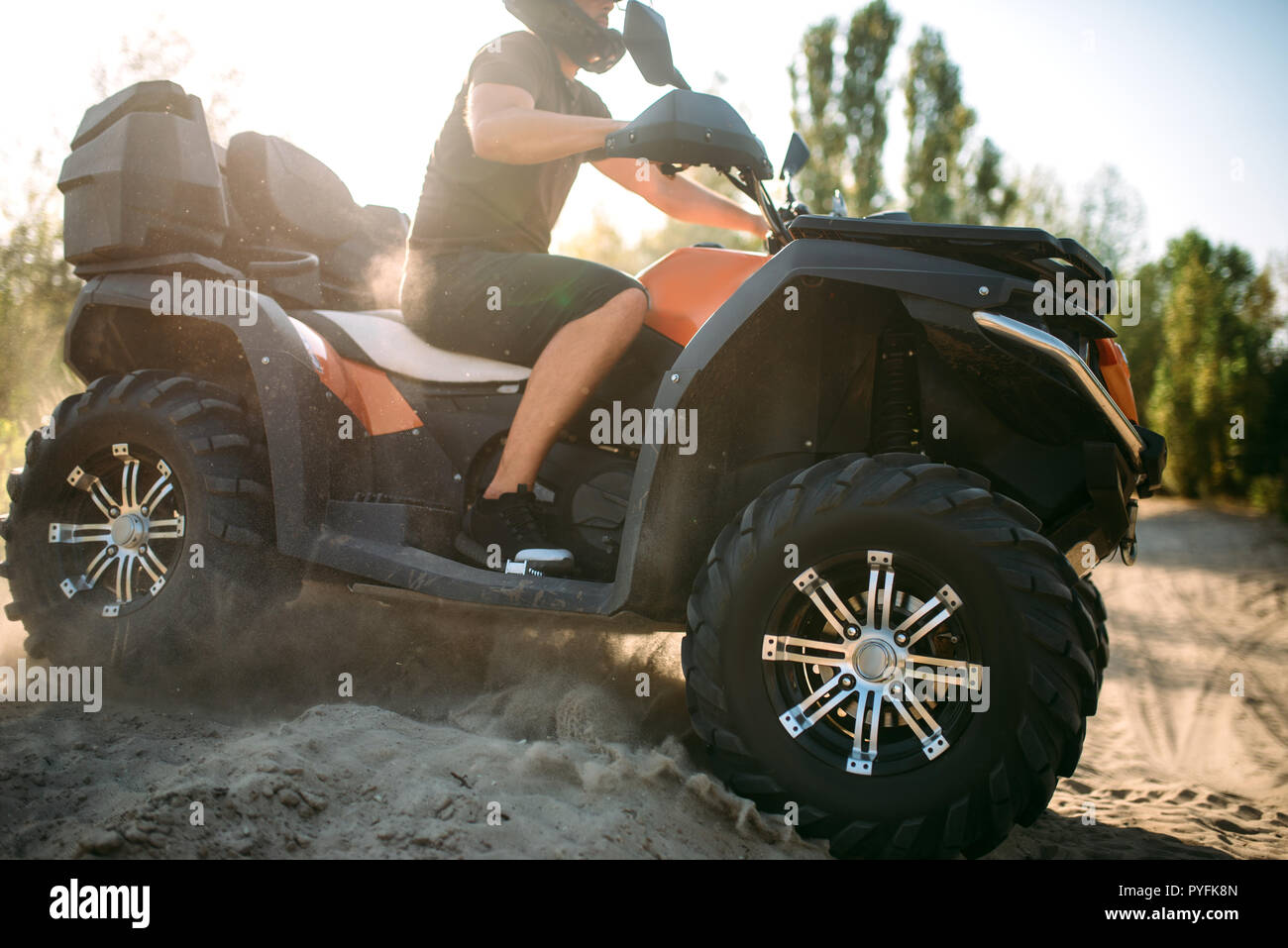 Atv rider in helmet rides on sandy road in forest. Riding on quad bike ...