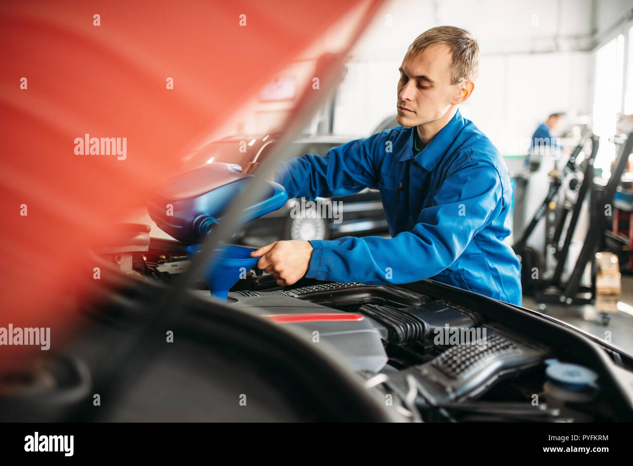 Technician pours new oil into the car engine. Vehicle engine ...