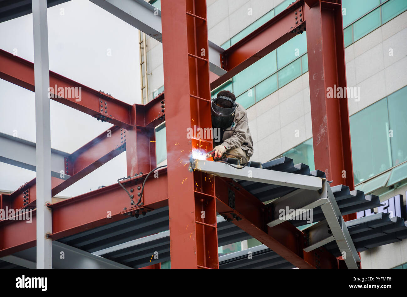 A workman welds steel girders high off the ground to construct the ...