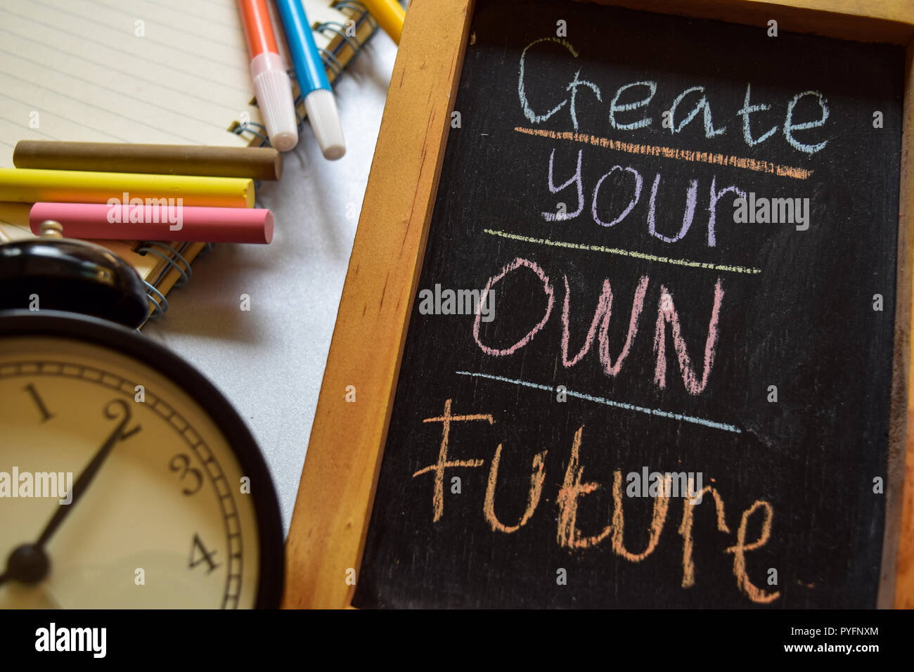Create your own future on phrase colorful handwritten on chalkboard, alarm clock with motivation ...