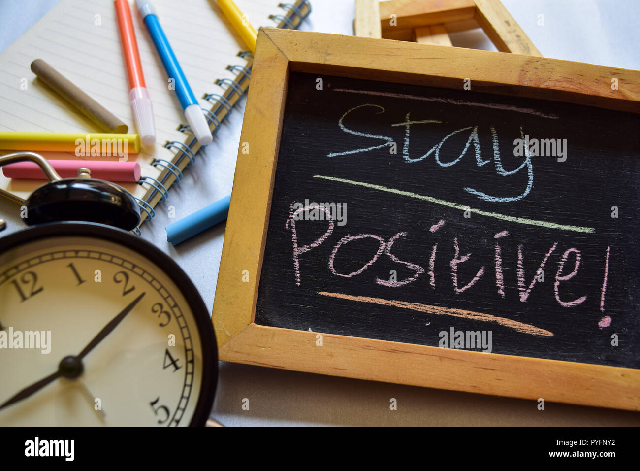 Stay positive on phrase colorful handwritten on chalkboard, alarm clock ...