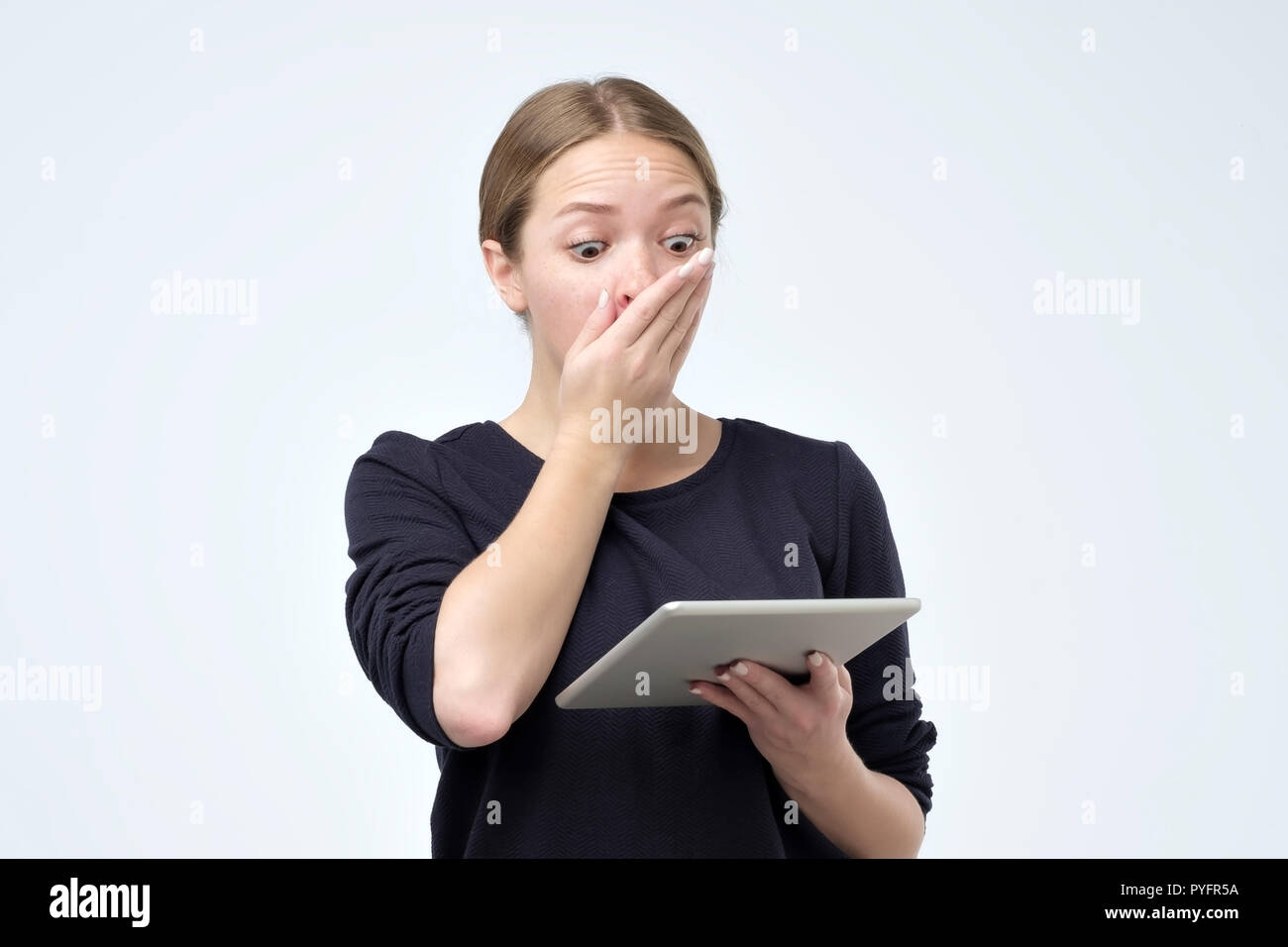 Shocked woman looking at digital tablet with surprise and shock over ...