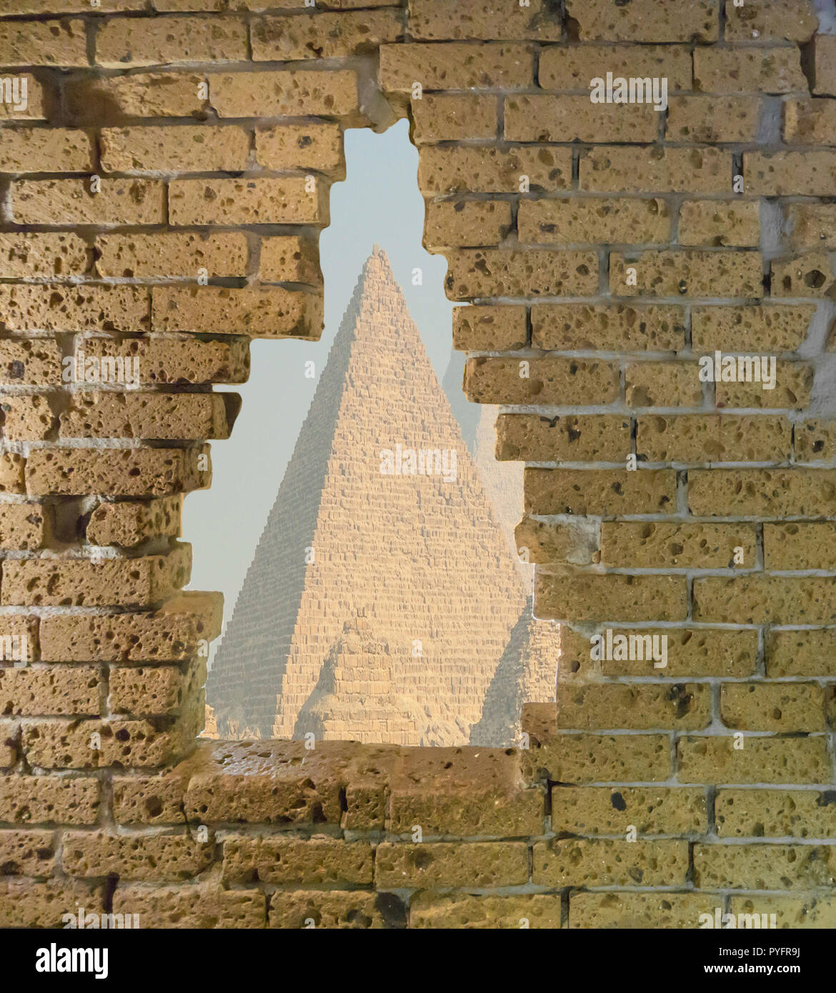 Old yellow brick wall in ruins with a big opening in it viewing on some ...