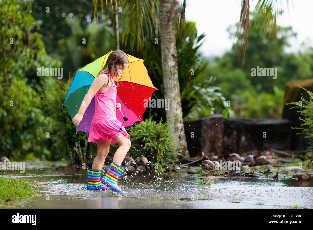 Kid playing out in the rain. Children with umbrella and rain boots play ...