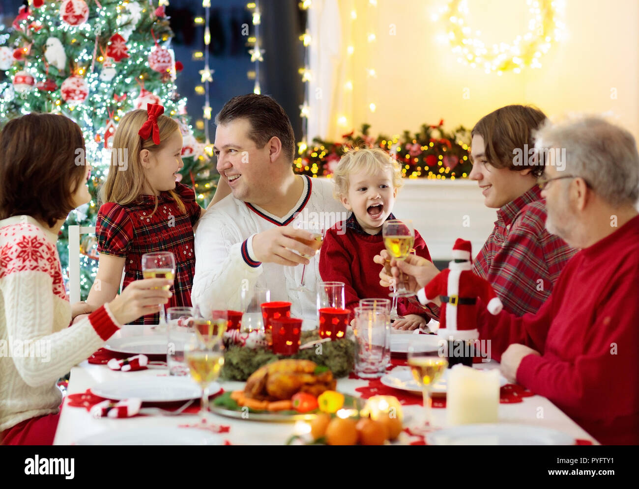 Family with children eating Christmas dinner at fireplace and decorated ...