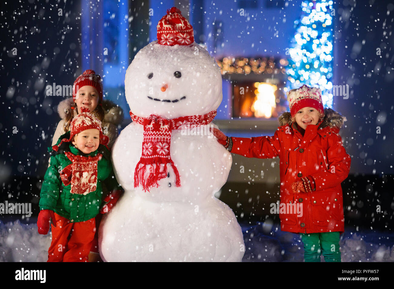 Kids build snowman on Christmas eve. Children in snowy backyard next to ...