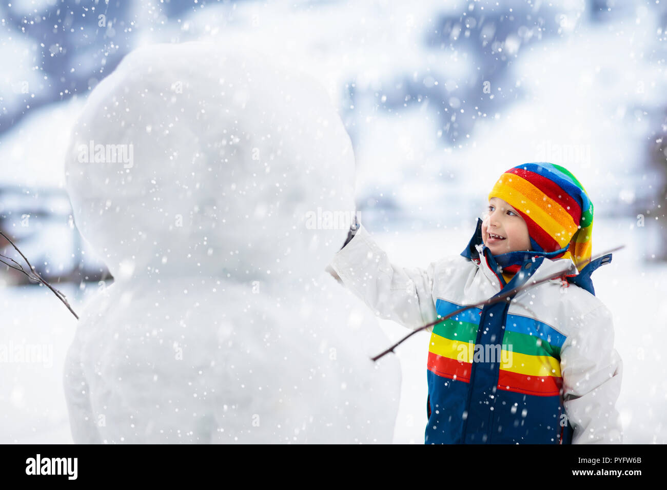 Child building snowman. Kids build snow man. Little boy playing ...