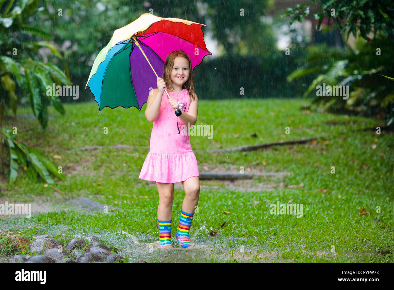 Kid playing out in the rain. Children with umbrella and rain boots play ...