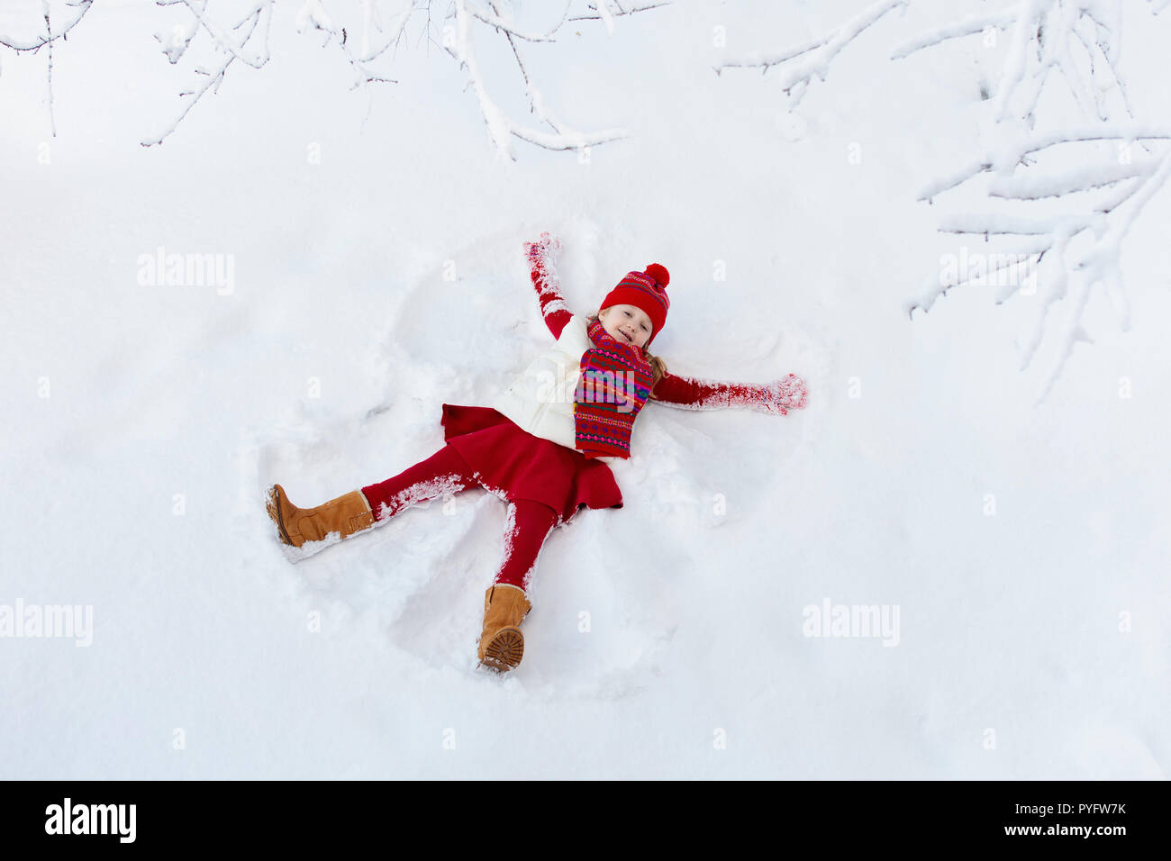 Child making snow angel on sunny winter morning. Kids winter outdoor ...