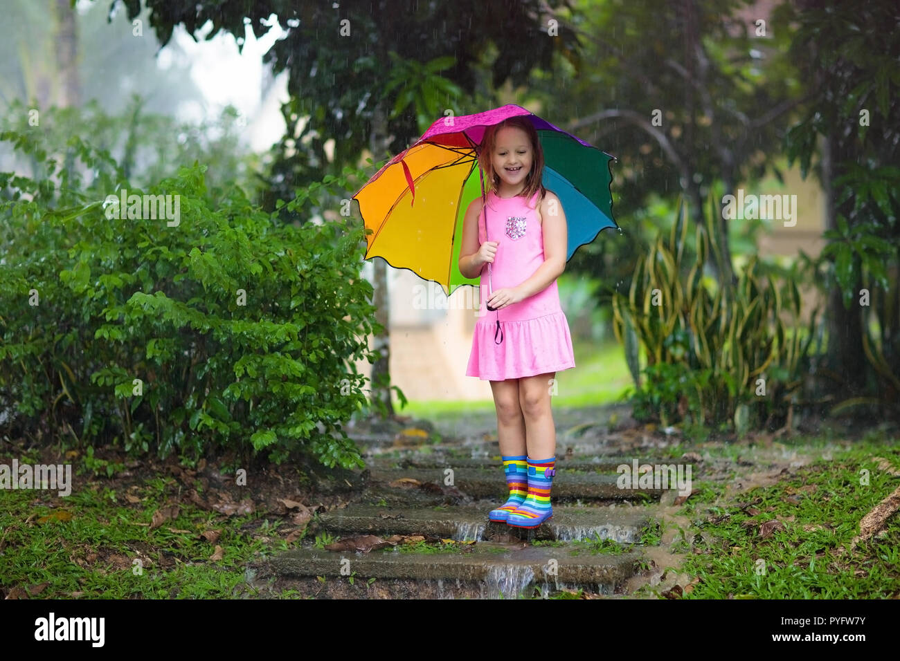 Kid playing out in the rain. Children with umbrella and rain boots play ...
