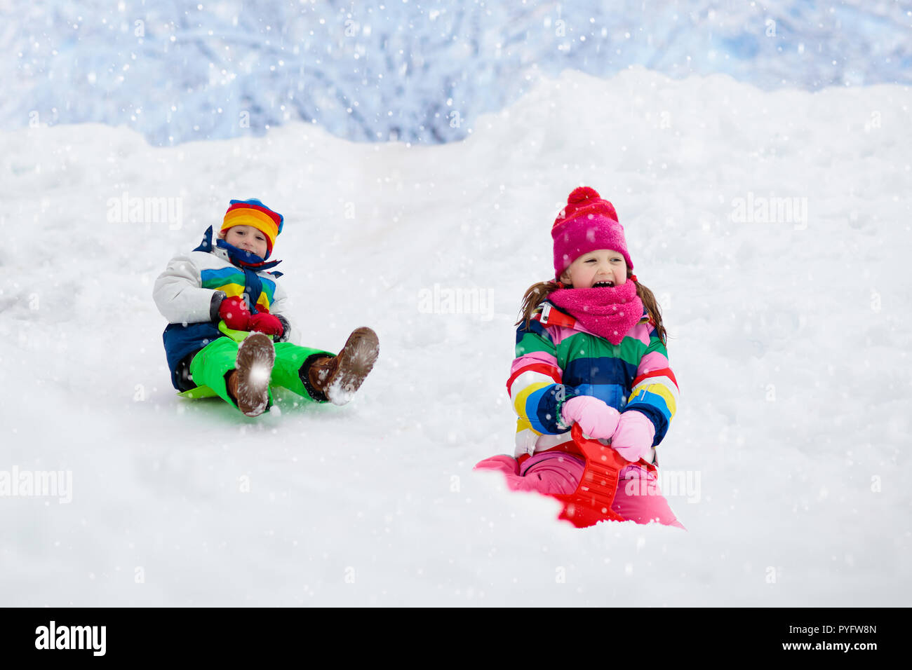 Little girl enjoying a sleigh ride. Child sledding. Toddler kid riding a sledge. Children play ...
